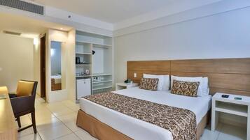 Quarto de hotel com uma cama grande, uma escrivaninha, uma cadeira e um guarda-roupa.