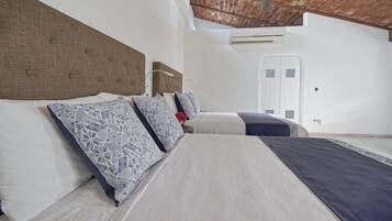 Quarto com uma cama grande, duas mesas de cabeceira, um ventilador de teto e uma porta branca.