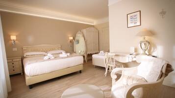 Quarto de hotel com uma cama grande, uma penteadeira com espelho, uma cadeira e uma escrivaninha.