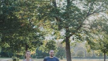 Duas pessoas correndo em um caminho de terra em um parque com árvores e grama.