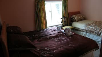 Quarto com uma cama de solteiro, uma cadeira e uma janela com cortinas.