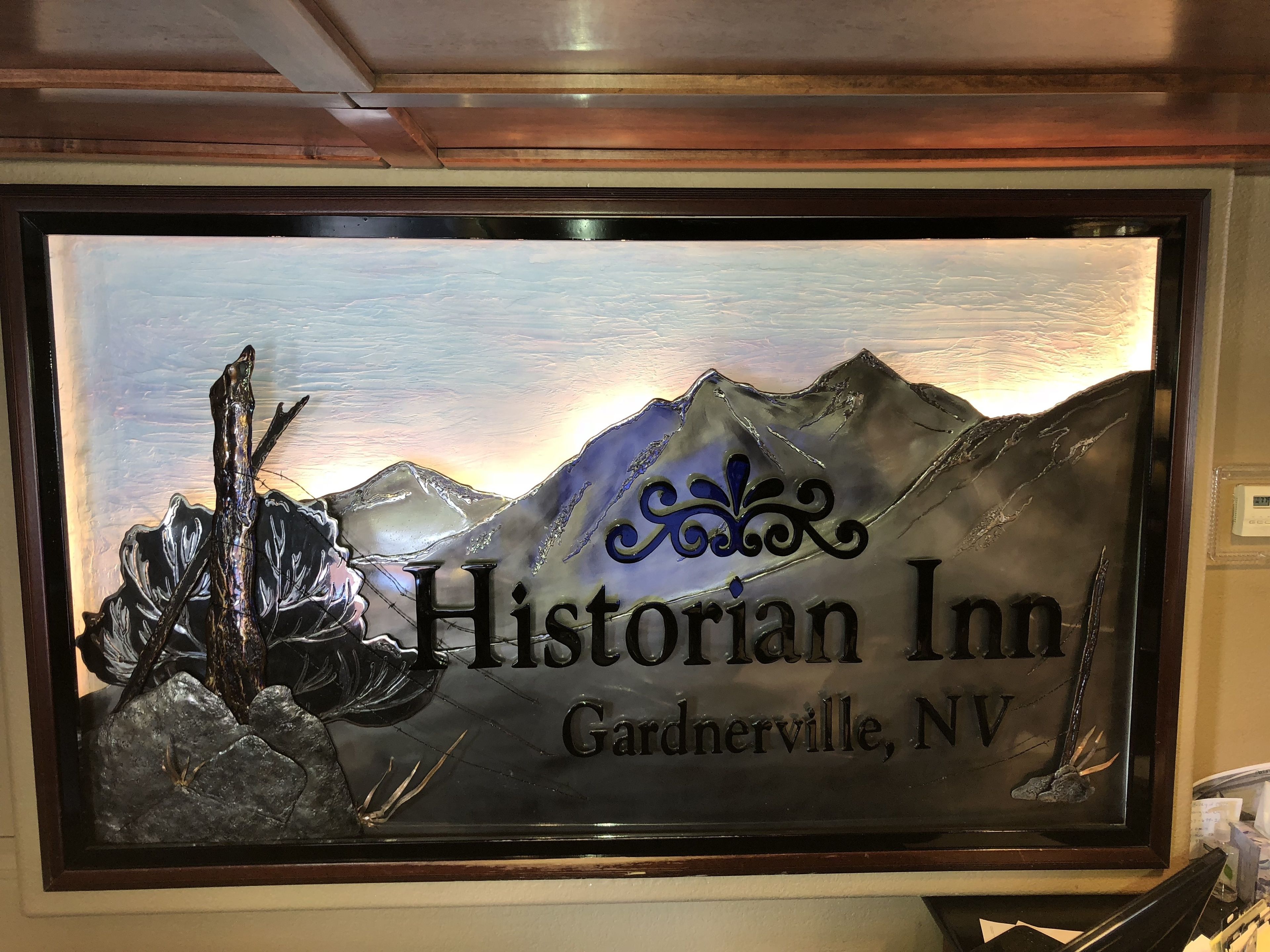 Placa emoldurada do Historian Inn em Gardnerville, Nevada, com paisagem de montanhas e detalhes decorativos.
