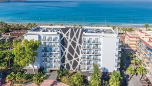 Um hotel moderno com fachada única, várias varandas e vista para o oceano.