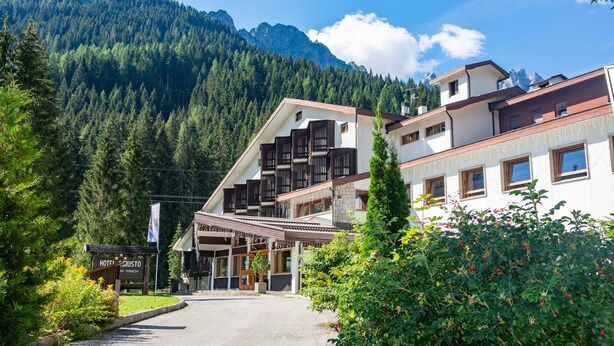 Hotel com montanhas ao fundo, destacando uma entrada imponente e uma placa.