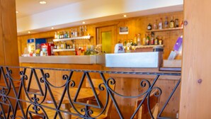 Uma área de bar com painéis de madeira, um balcão e prateleiras com garrafas.