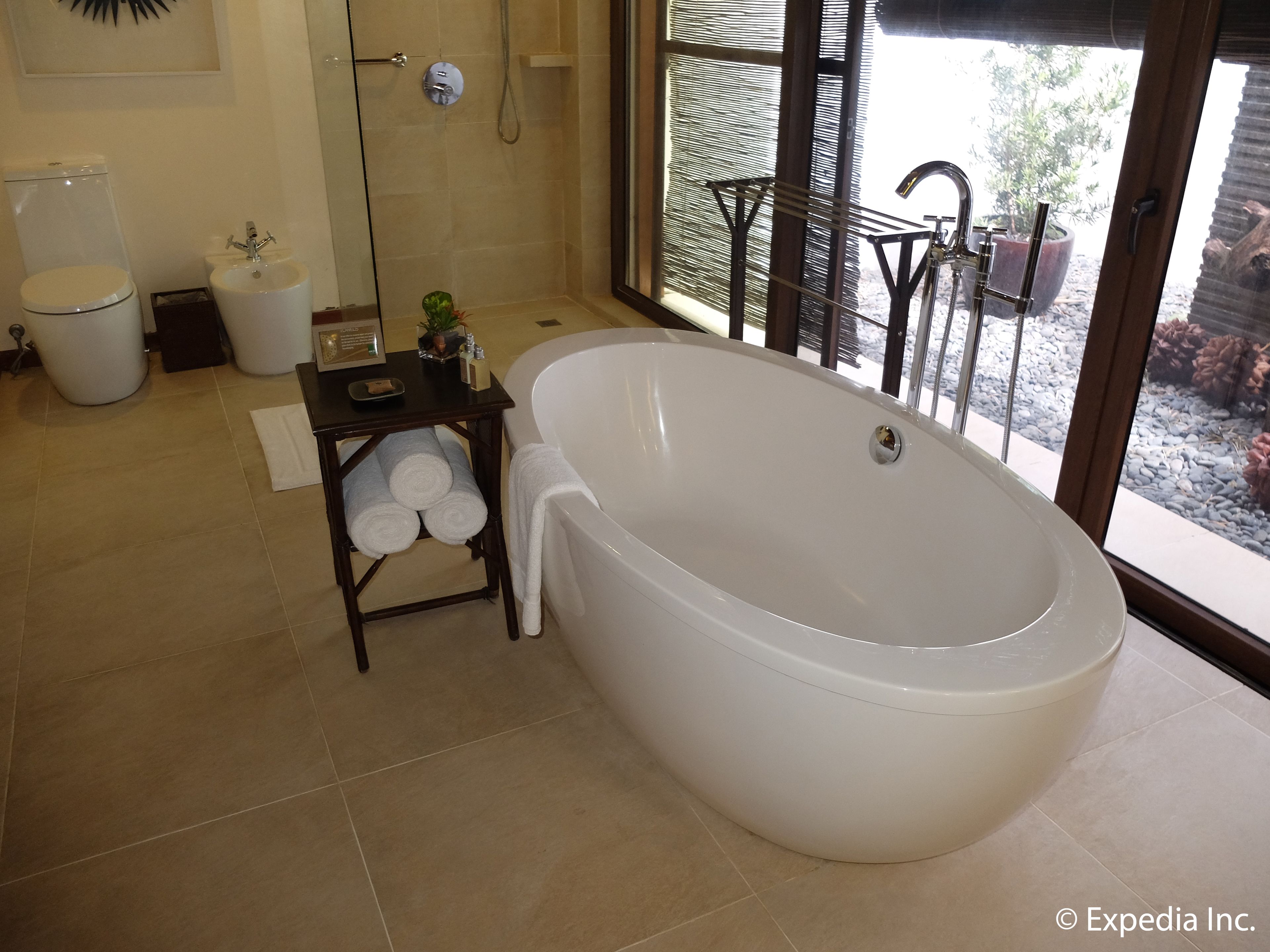 Um banheiro espaçoso com uma banheira de imersão grande, chuveiro com box de vidro e vista para o exterior.