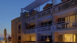 Um hotel moderno com piscina, várias varandas e áreas de estar ao ar livre.