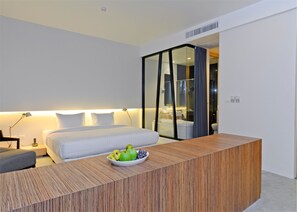Quarto de hotel moderno com uma cama grande, uma secretária de madeira e uma fruteira.