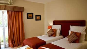 Quarto de hotel com duas camas, um candelabro e vista para o exterior.
