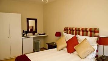 Quarto de hotel com cama, mesas de cabeceira, guarda-roupa, espelho e radiador.