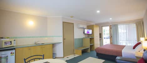 Quarto de hotel compacto com cozinha compacta, área de refeições, cama e espaço para sentar.