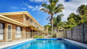 Uma piscina com cerca de madeira e um prédio com varanda.