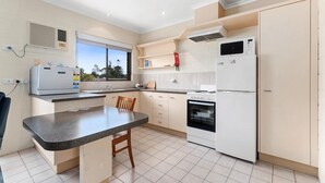 Uma cozinha moderna com ilha central, forno embutido e frigorífico.