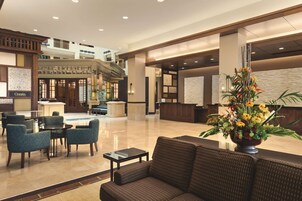 Um hall amplo com balcão de recepção, área de estar e um arranjo floral decorativo.