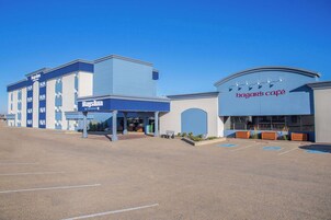 Um edifício com fachada azul e branca, um letreiro com 'Hagar's Café' e um estacionamento com vagas demarcadas.