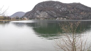 Um lago tranquilo com uma montanha ao fundo e alguns edifícios perto da margem.