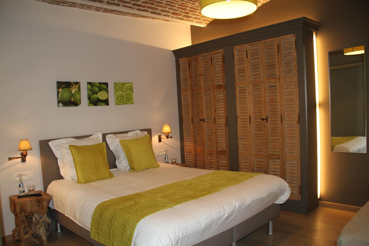 Quarto com cama grande, guarda-roupa de madeira e obra de arte na parede.