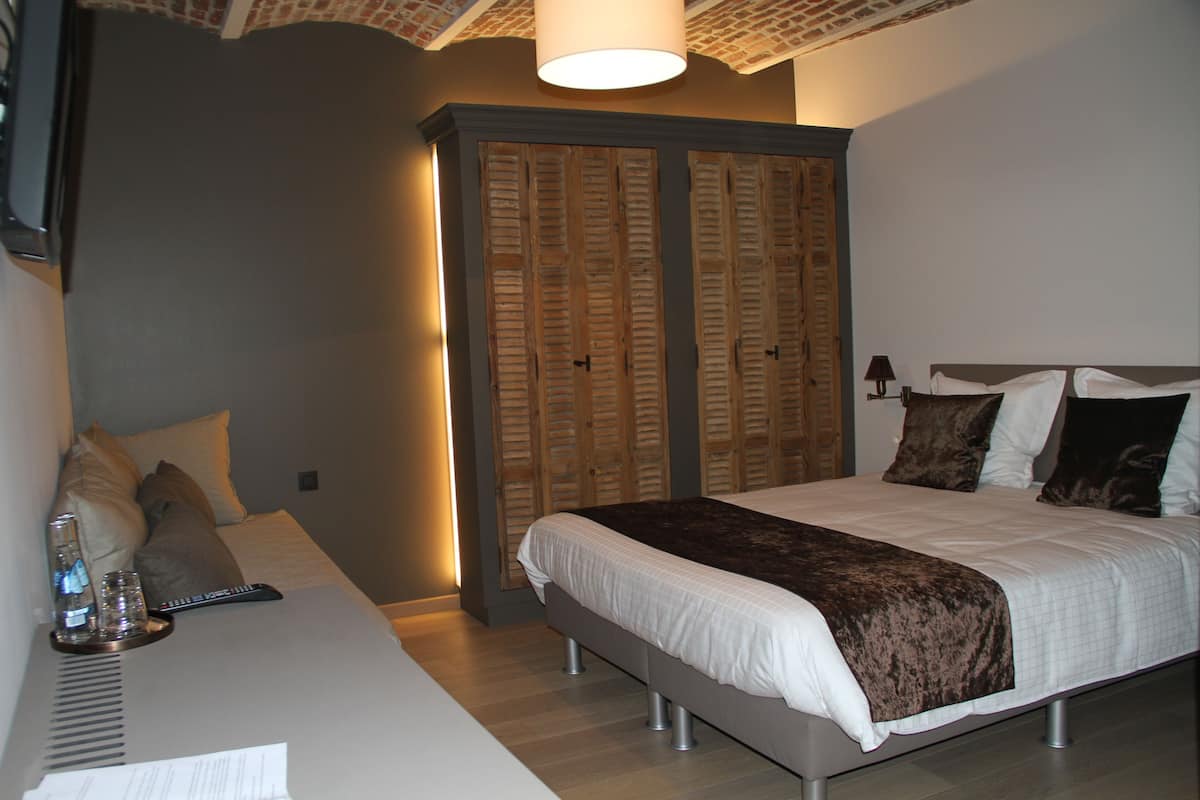 Quarto moderno com cama grande, escrivaninha com controle remoto e guarda-roupa com portas de madeira.