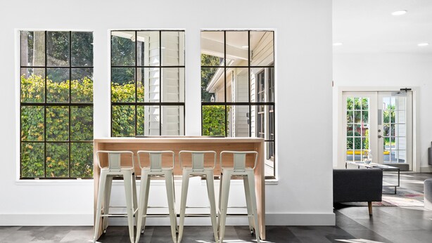 Um interior moderno com área de bar, janelas amplas e vista para o verde lá fora.