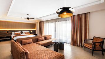Quarto de hotel com uma cama, um sofá, uma cadeira, uma mesa e um ventilador de teto.