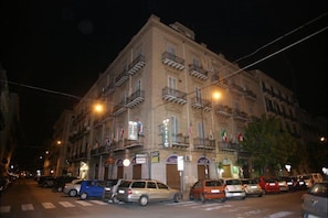 Um edifício com vários andares, varandas, janelas para a rua e bandeiras.