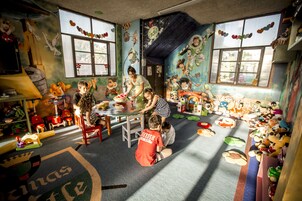 Quarto com área de recreação, uma janela grande e um mural na parede.