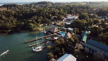 Um resort costeiro com uma marina, construções com telhados de palha e um edifício grande com telhado verde.