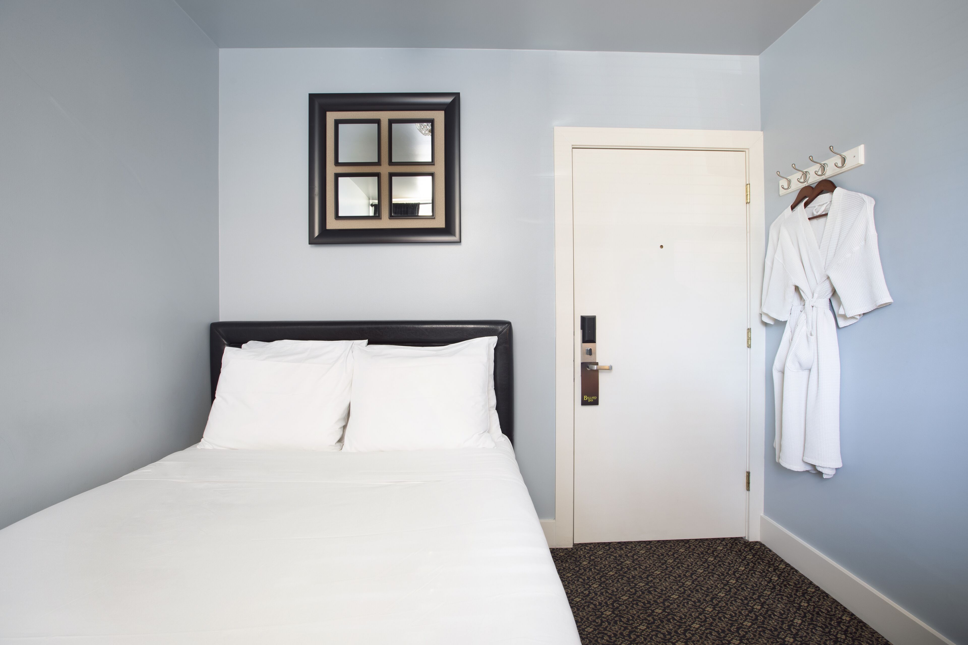 Quarto de hotel com uma cama, uma porta e um roupão pendurado em um gancho.