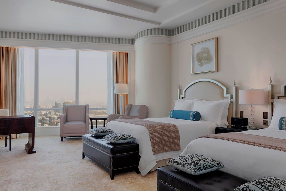 Quarto de hotel com uma cama grande, uma cadeira, uma escrivaninha e vista para a cidade.