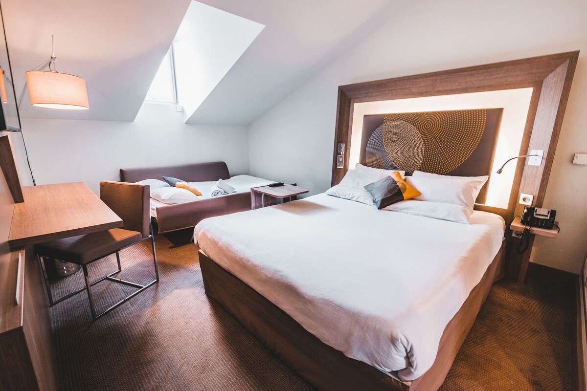 Quarto de hotel moderno com uma cama grande, uma mesa e um espaço de estar.