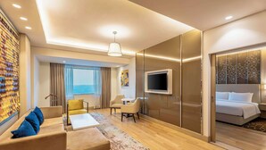 Quarto de hotel moderno com sofá, poltrona e cama.