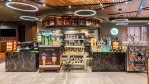 Uma área de bar com balcão circular, prateleiras com garrafas de bebidas e uma placa com a inscrição 'The Low Bar'.
