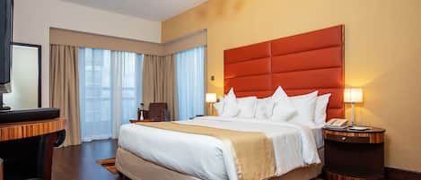 Quarto de hotel com uma cama grande, uma escrivaninha e uma cadeira.