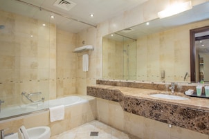 Uma casa de banho moderna com cabine de duche em vidro, banheira, lavatório e toucador com bancada de mármore.