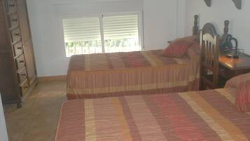 Quarto com duas camas, uma cômoda e uma janela com persianas.
