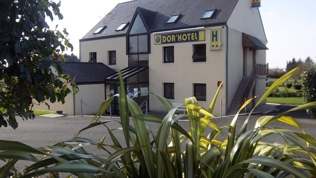 Um edifício de dois andares com uma placa que diz "DOR HOTEL" e um símbolo de hospital indicando instalações médicas no local.