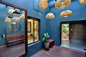 Um interior moderno com um banco de madeira, uma planta em vaso e luminárias pendentes de vime.