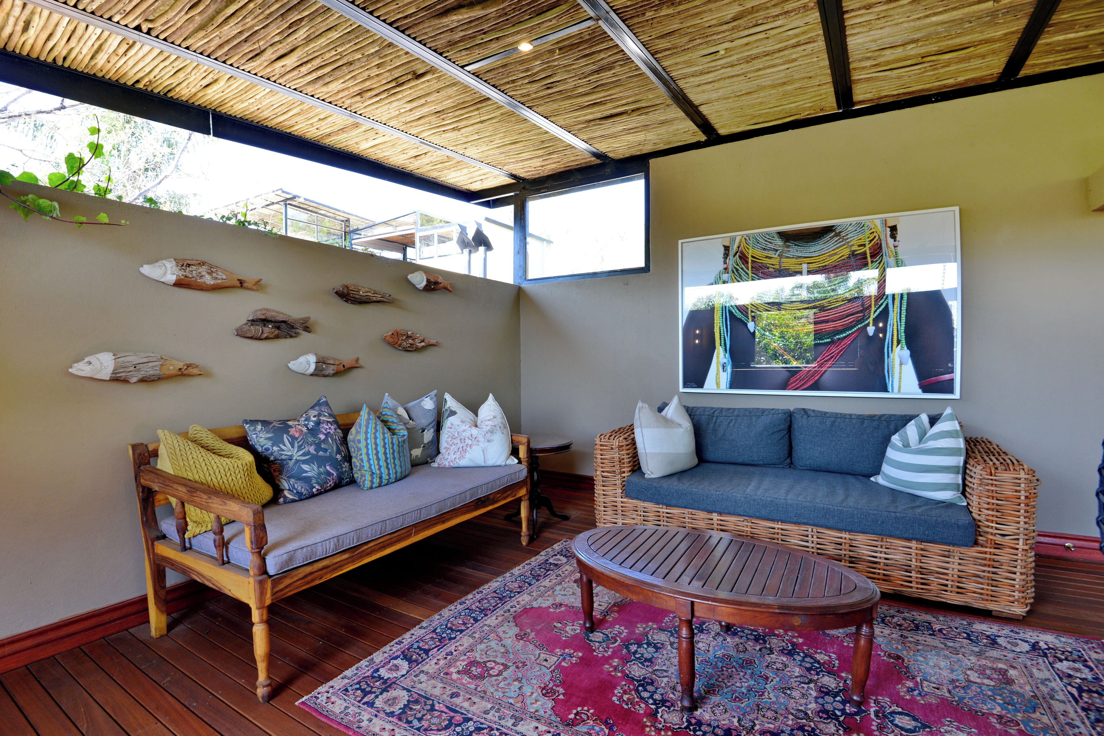 Quarto com piso de madeira, um sofá com almofadas, uma mesa de centro e uma parede decorada com peixes.