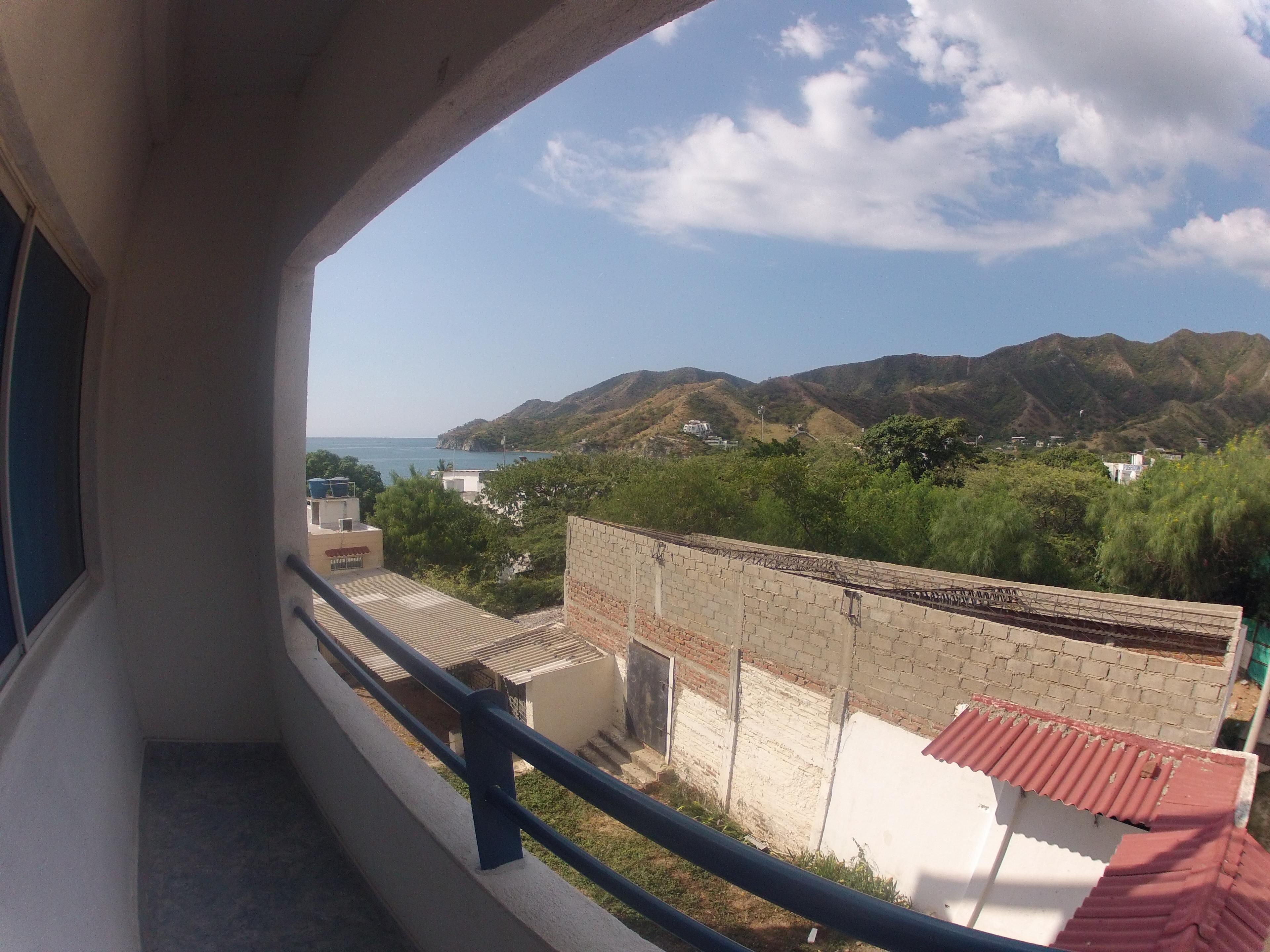 Uma varanda com vista para uma paisagem montanhosa e um corpo de água.
