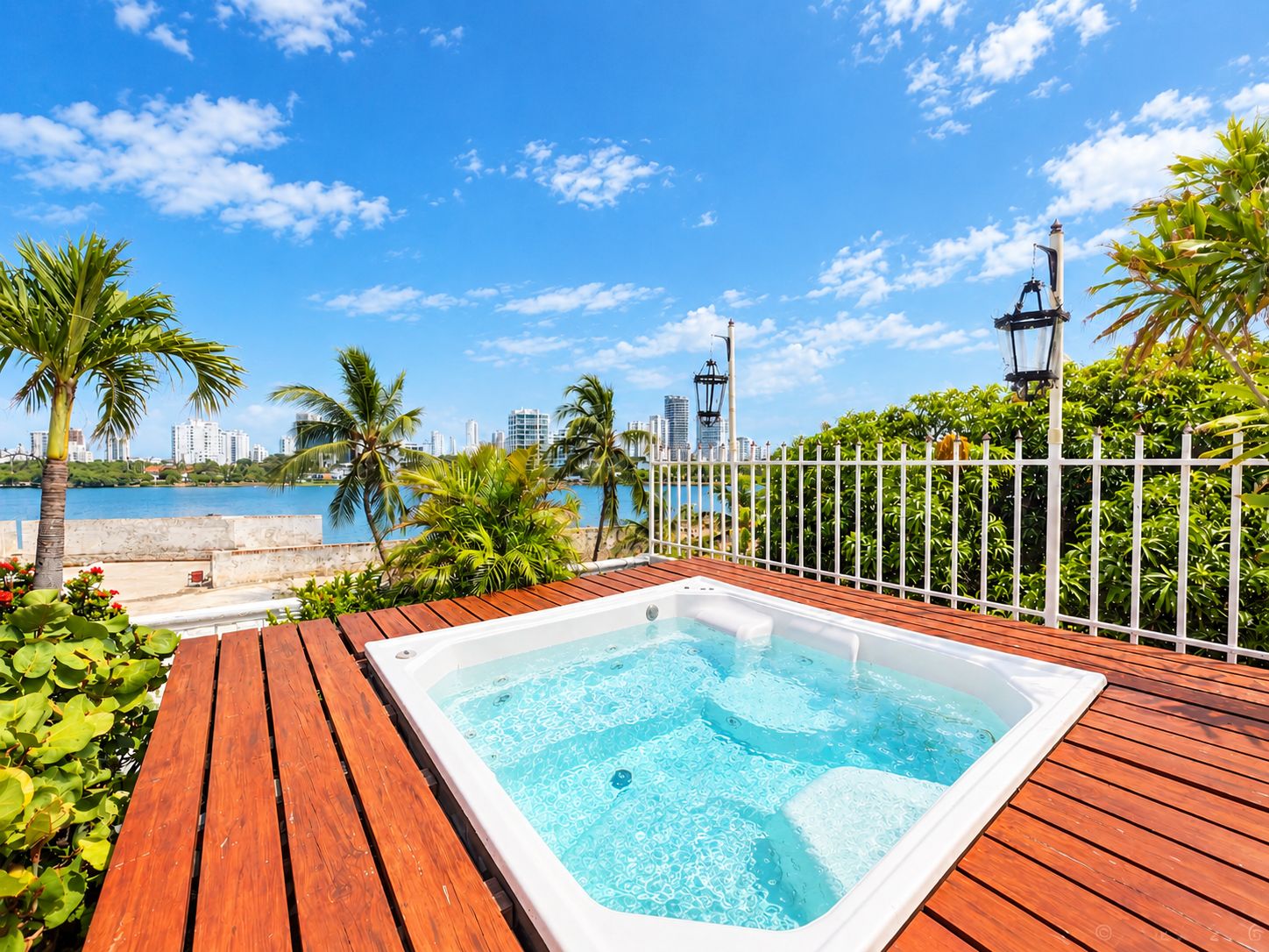 Um deck de madeira com hidromassagem, palmeiras e vista para o horizonte urbano.