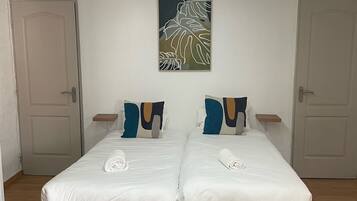 Quarto duplo com duas camas, uma luminária no teto e uma obra de arte na parede.