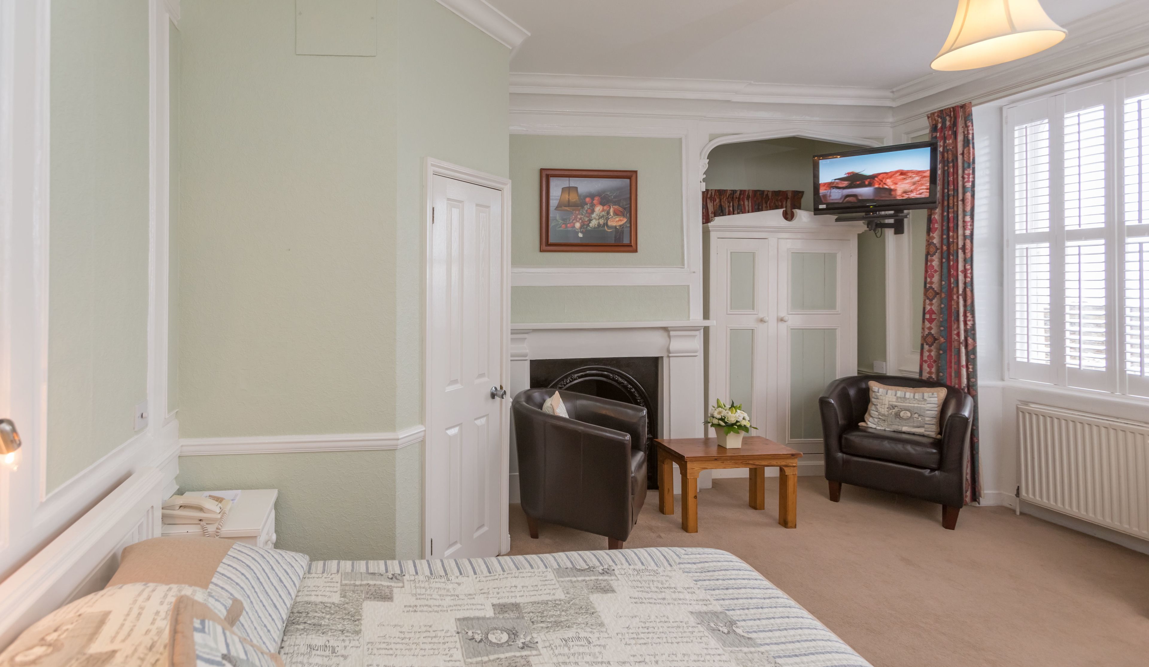 Quarto de hotel com uma cama, lareira, televisão e janela com cortinas.