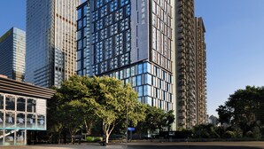 Um edifício moderno com fachada de vidro, várias varandas e uma sinalização destacada.