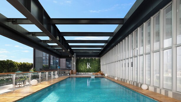 Piscina interna moderna com vista clara para o céu, deck de madeira e parede de vidro com a letra 'K'.