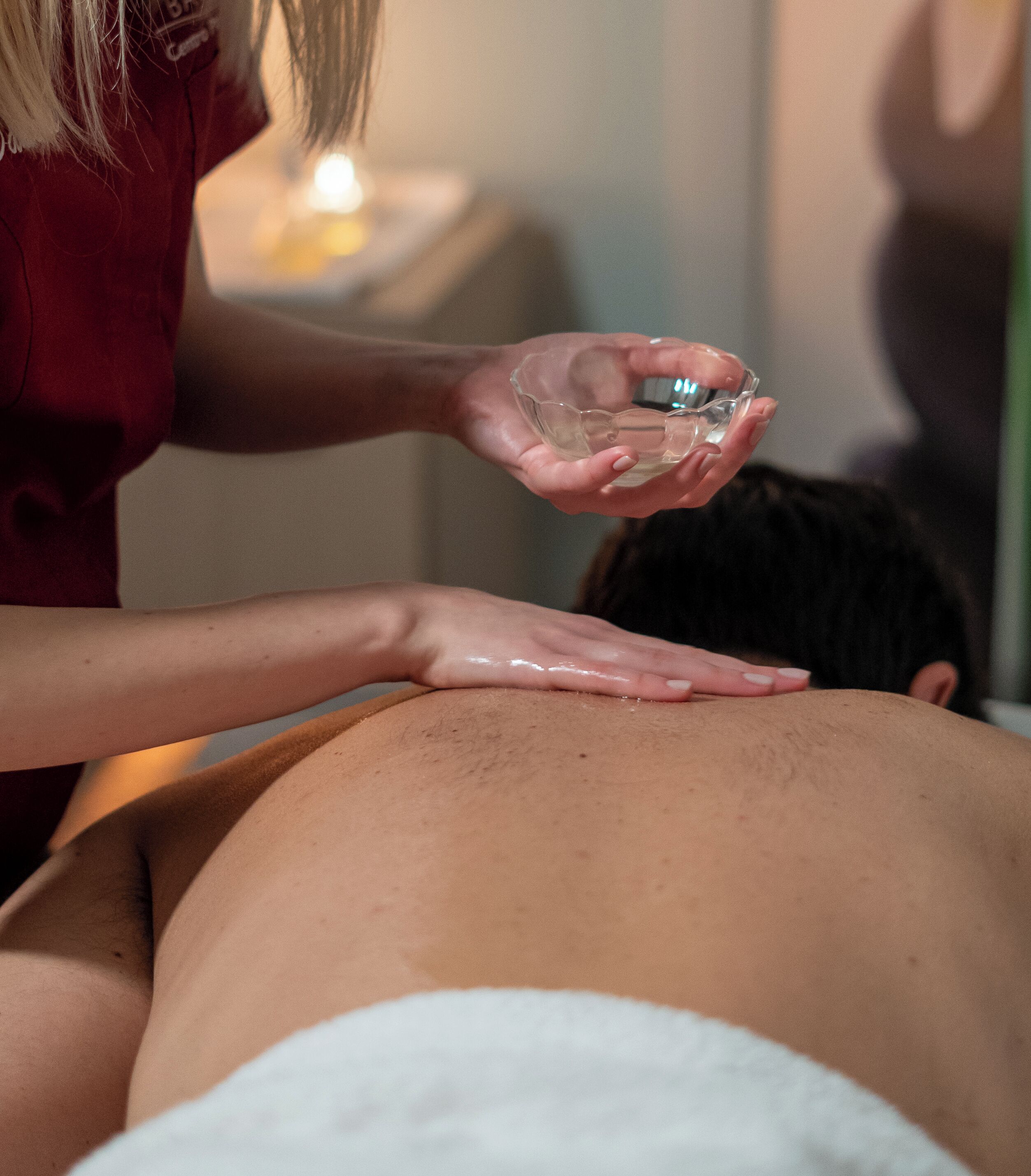 Uma pessoa recebendo massagem com um recipiente de vidro transparente nas costas.