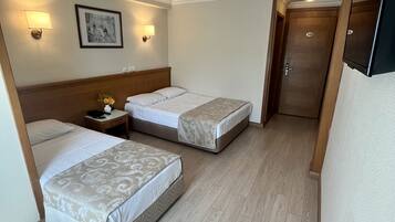 Quarto de hotel com duas camas, uma escrivaninha, uma cadeira e um guarda-roupa.