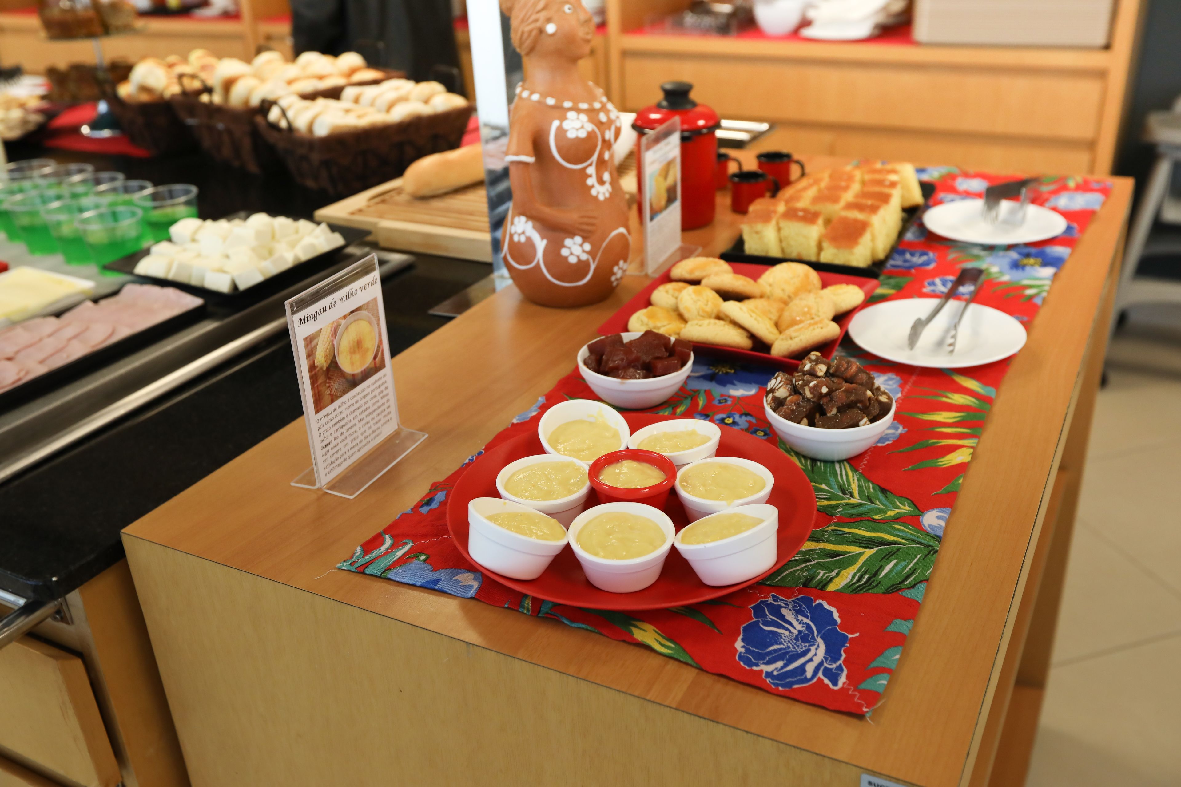 Uma mesa de buffet com diversos alimentos, incluindo doces, patês e uma figura decorativa de cerâmica.