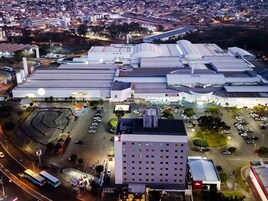 Uma área industrial com edifícios grandes, estacionamento e estação de ônibus.