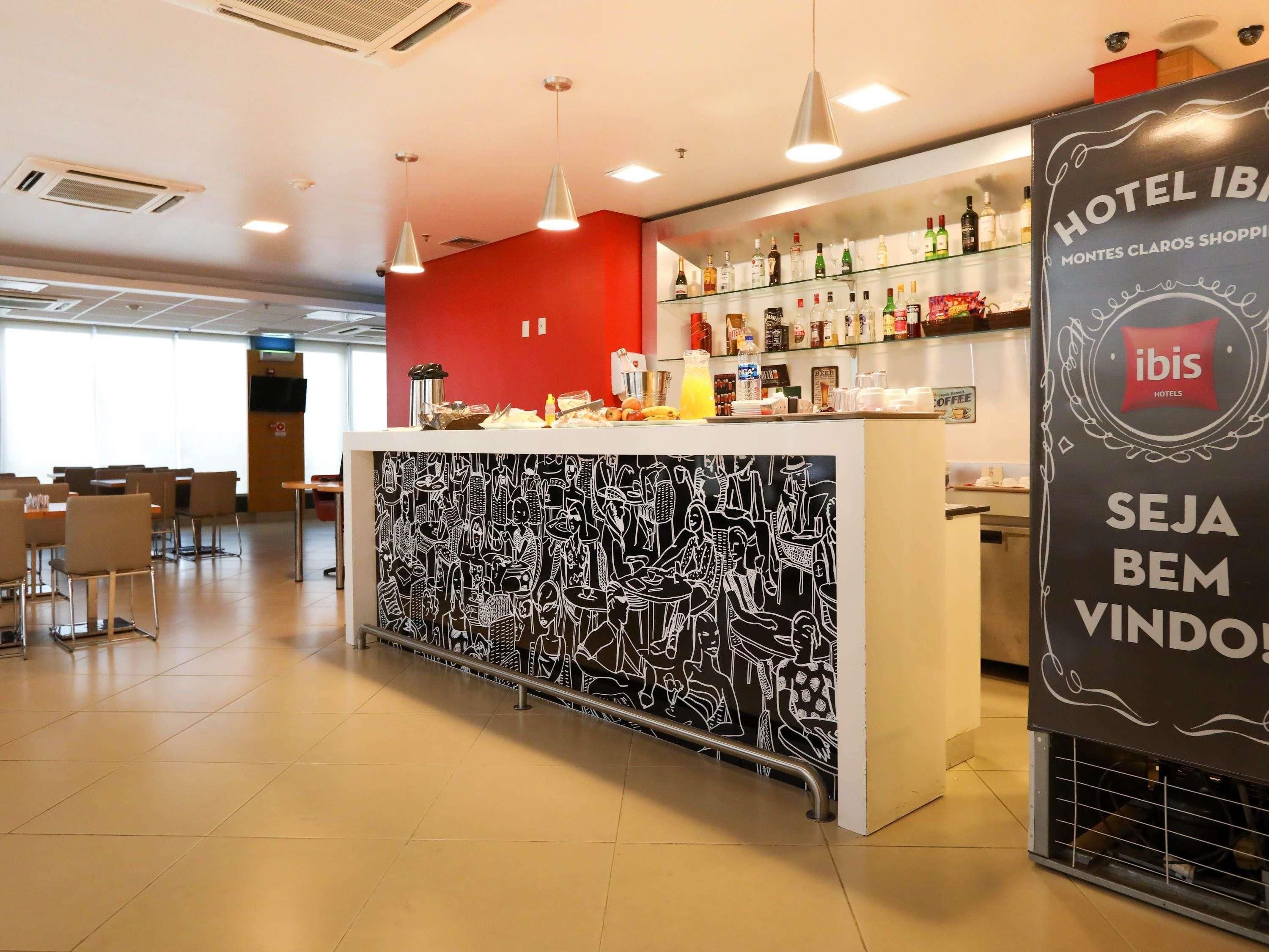 Um saguão de hotel com área de bar, assentos e um grande anúncio da marca ibis.