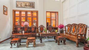 Um quarto espaçoso com mobiliário de madeira ornamentado, amplas janelas e design clássico.